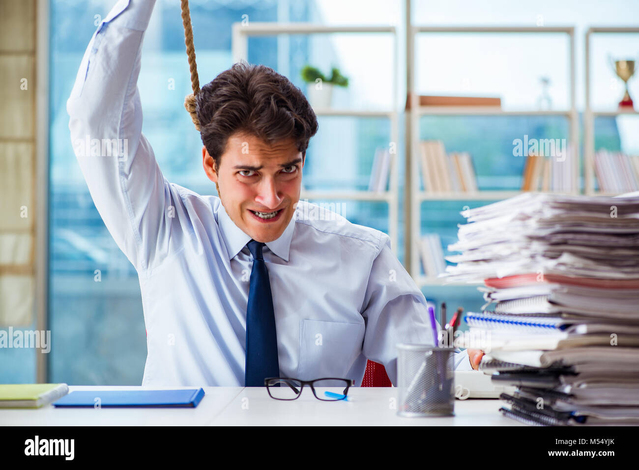 The unhappy businessman thinking of hanging himself in the office Stock ...