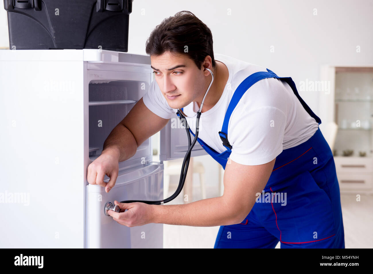 The repairman contractor repairing fridge in diy concept Stock Photo ...