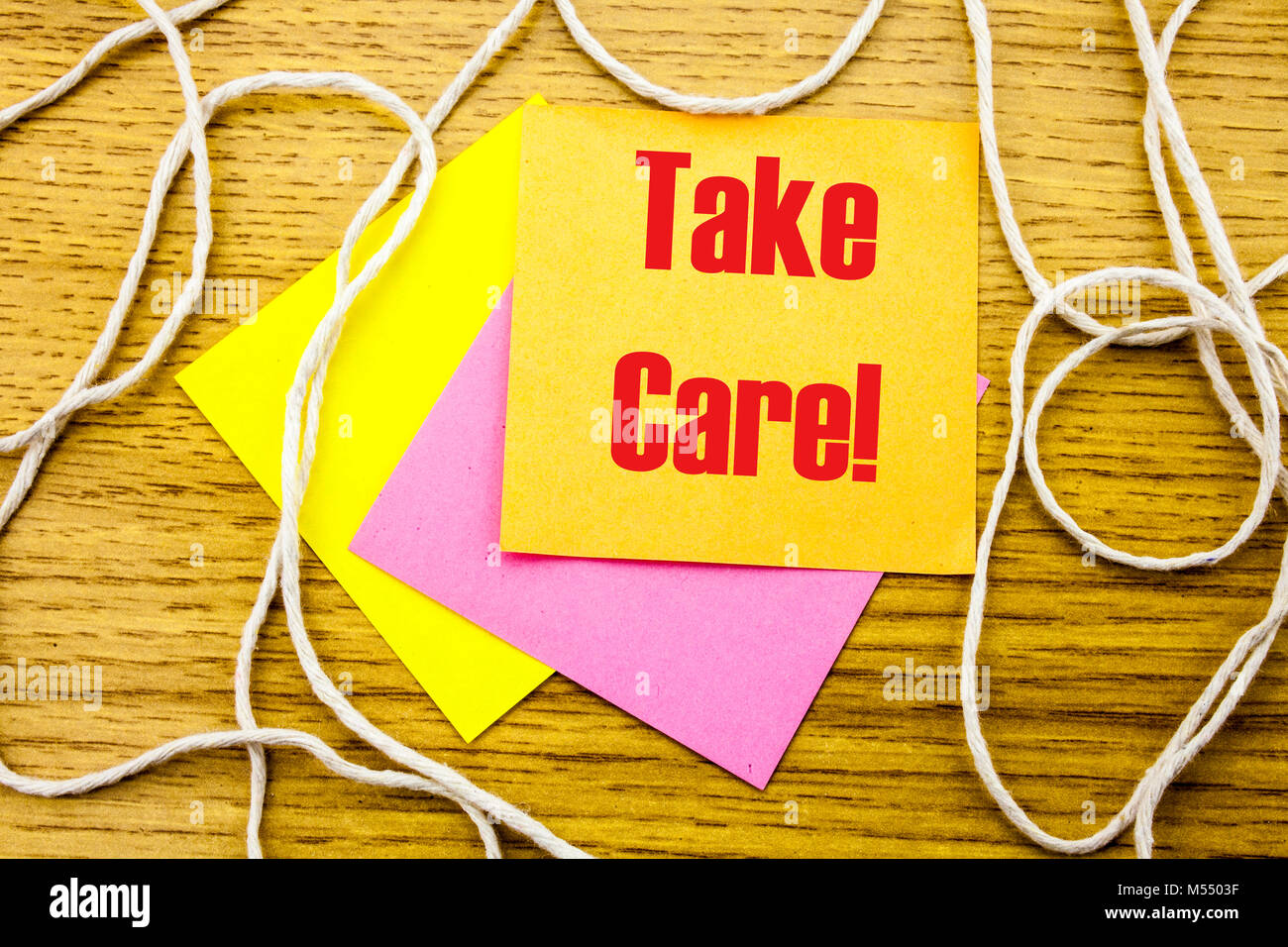 Take care- word on yellow sticky note in wooden background. Bussines ...