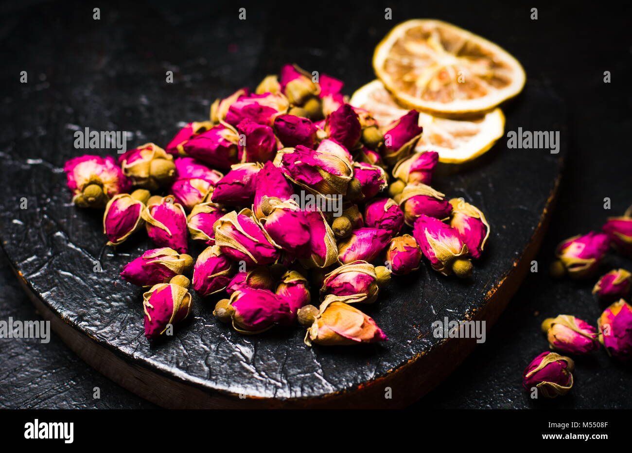 Rose tea buds and lemon slices on dark plate Stock Photo - Alamy