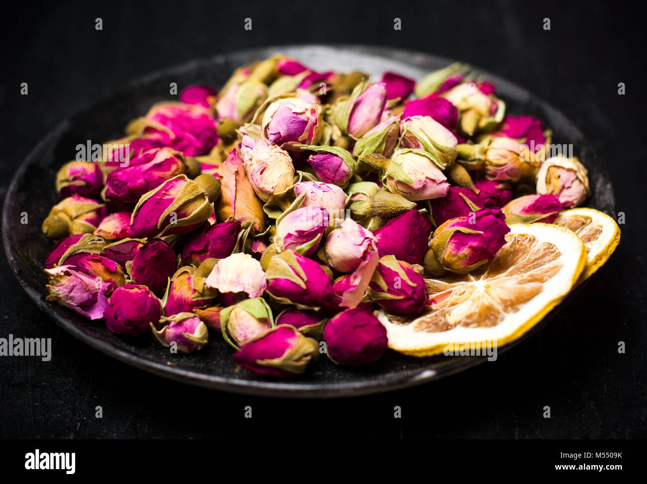 Rose tea buds and lemon slices on dark plate Stock Photo - Alamy