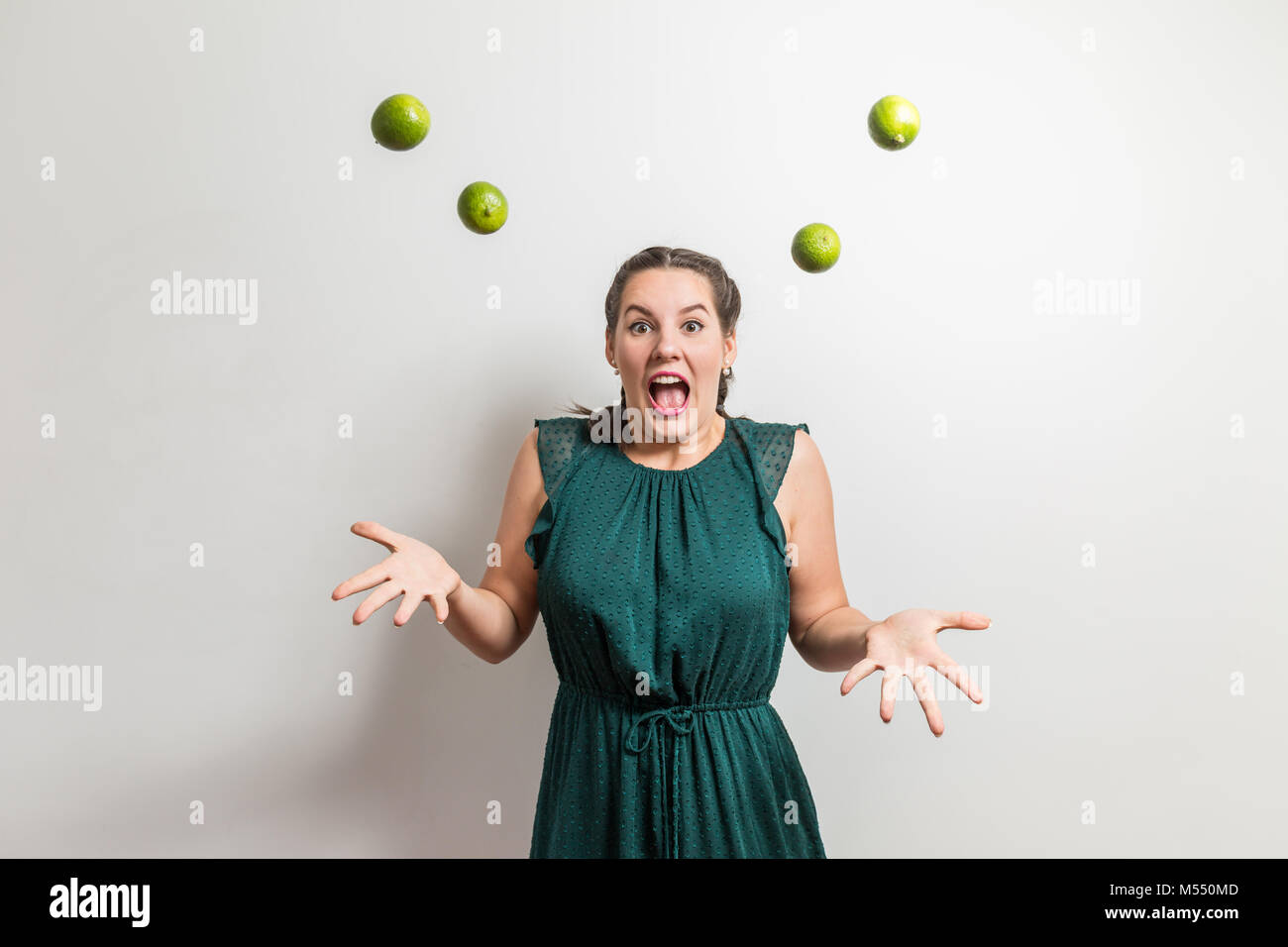 Screaming girl throws lime fruits in the air Stock Photo - Alamy