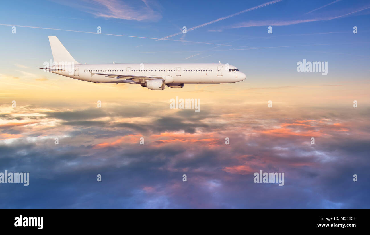 Commercial airplane jetliner flying above clouds in beautiful sunset ...