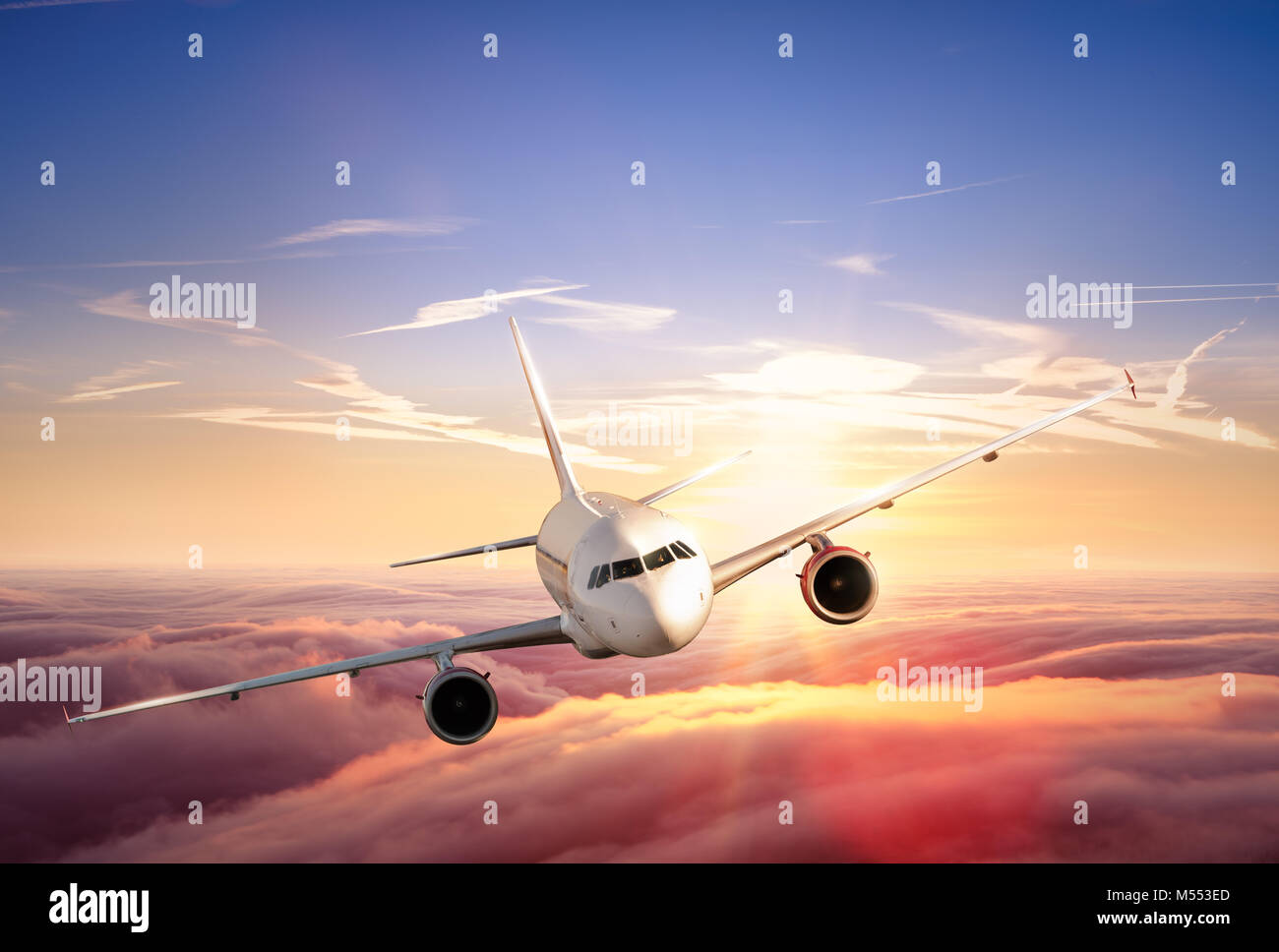 Commercial airplane jetliner flying above clouds in beautiful sunset ...