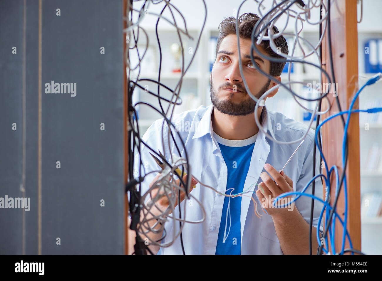 Electrician trying to untangle wires in repair concept Stock Photo - Alamy
