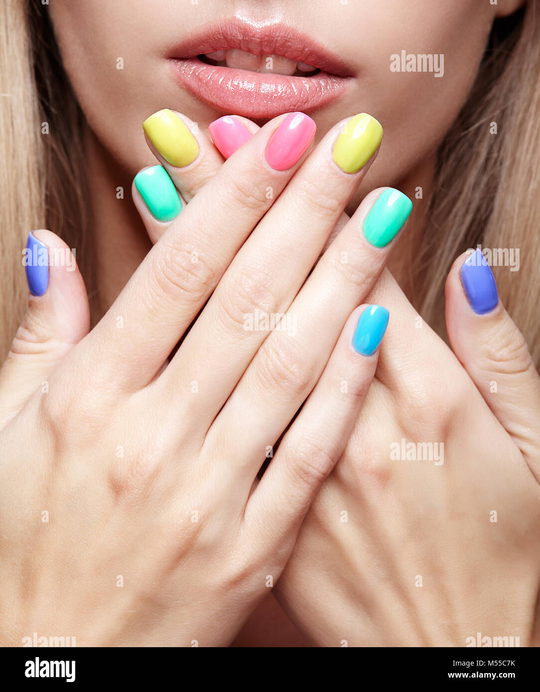 Young blonde woman with fun varicoloured finger nails manicure Stock ...