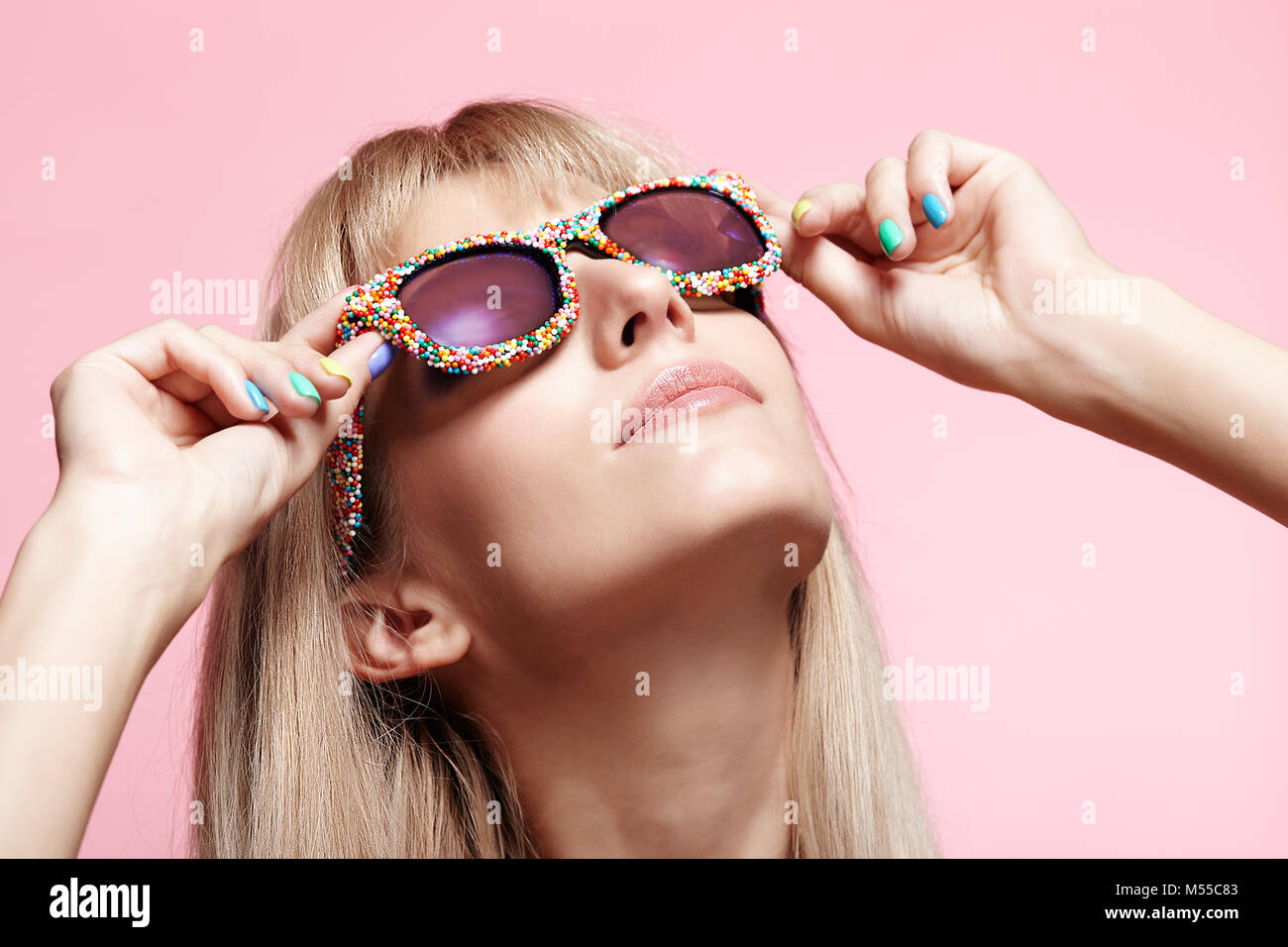 Young blonde woman with fun candy glasses on pink background Stock ...