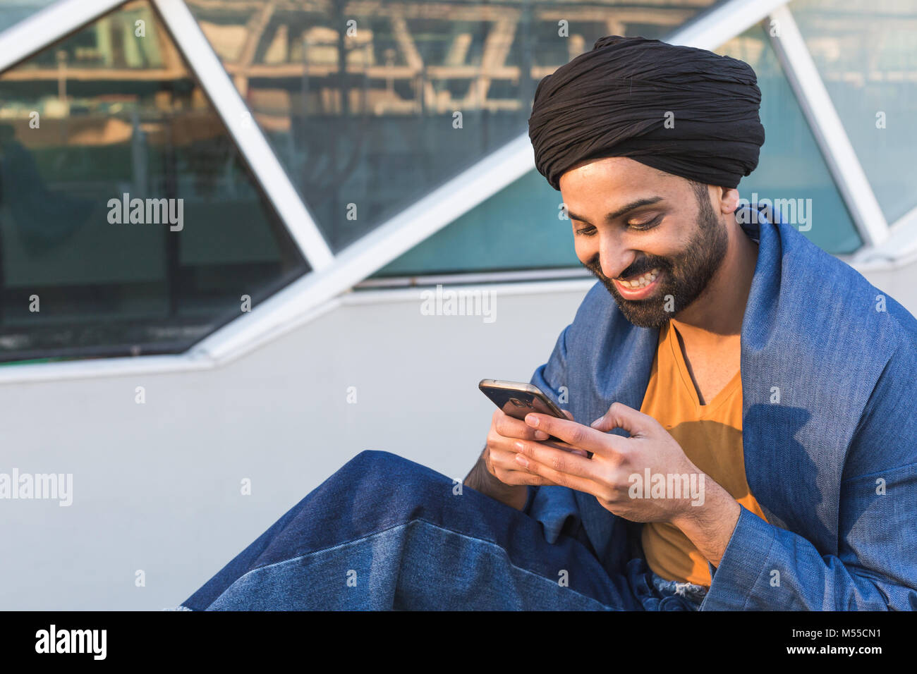 Handsome Indian man texting in an urban context. Street fashion and ...