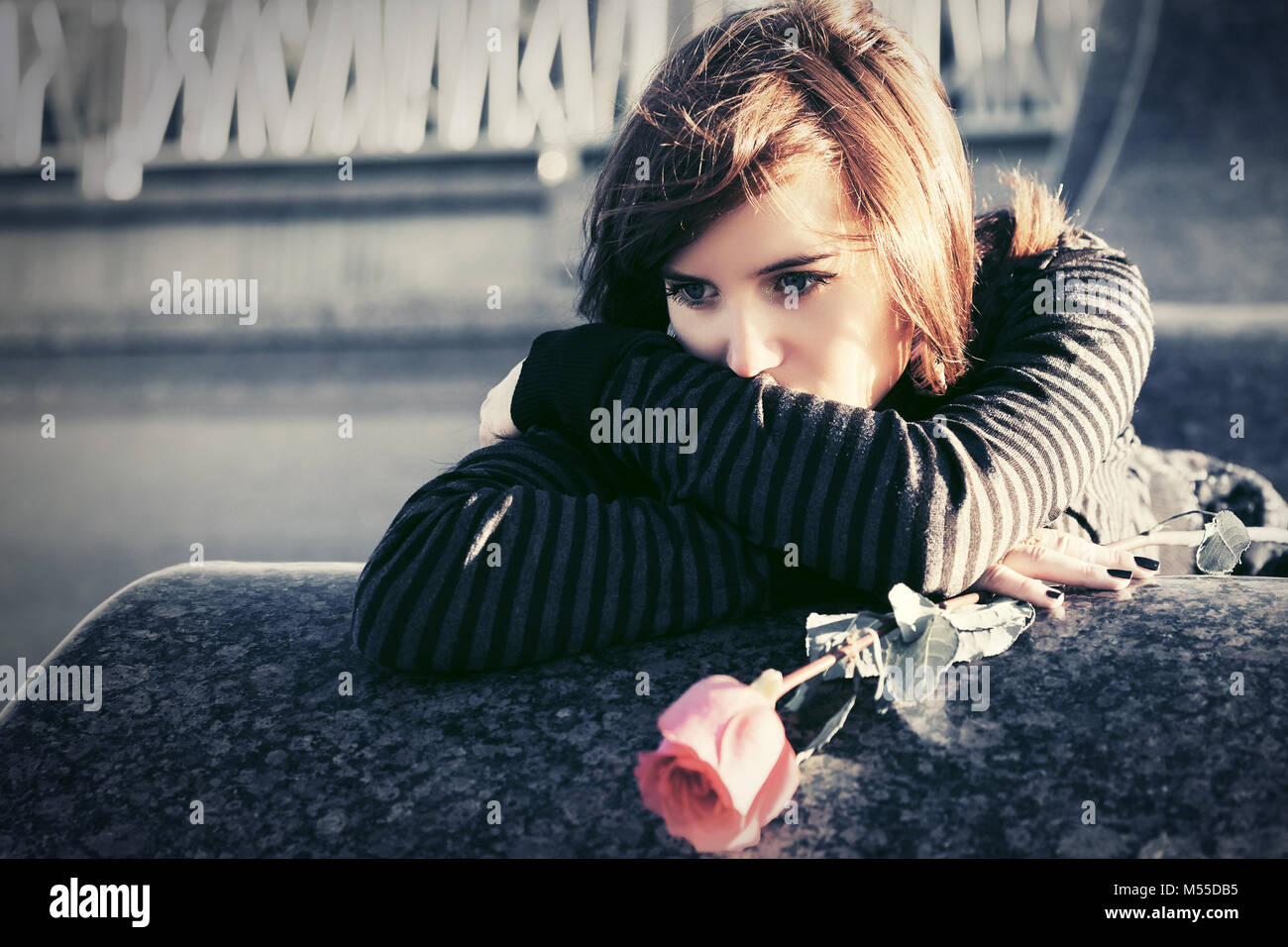 Sad young woman with a red rose on city street Stock Photo - Alamy
