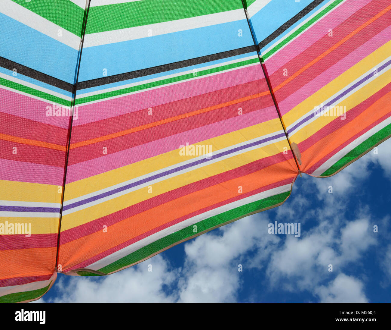 Close-up bright multicolor striped beach parasols in backlit of summer ...