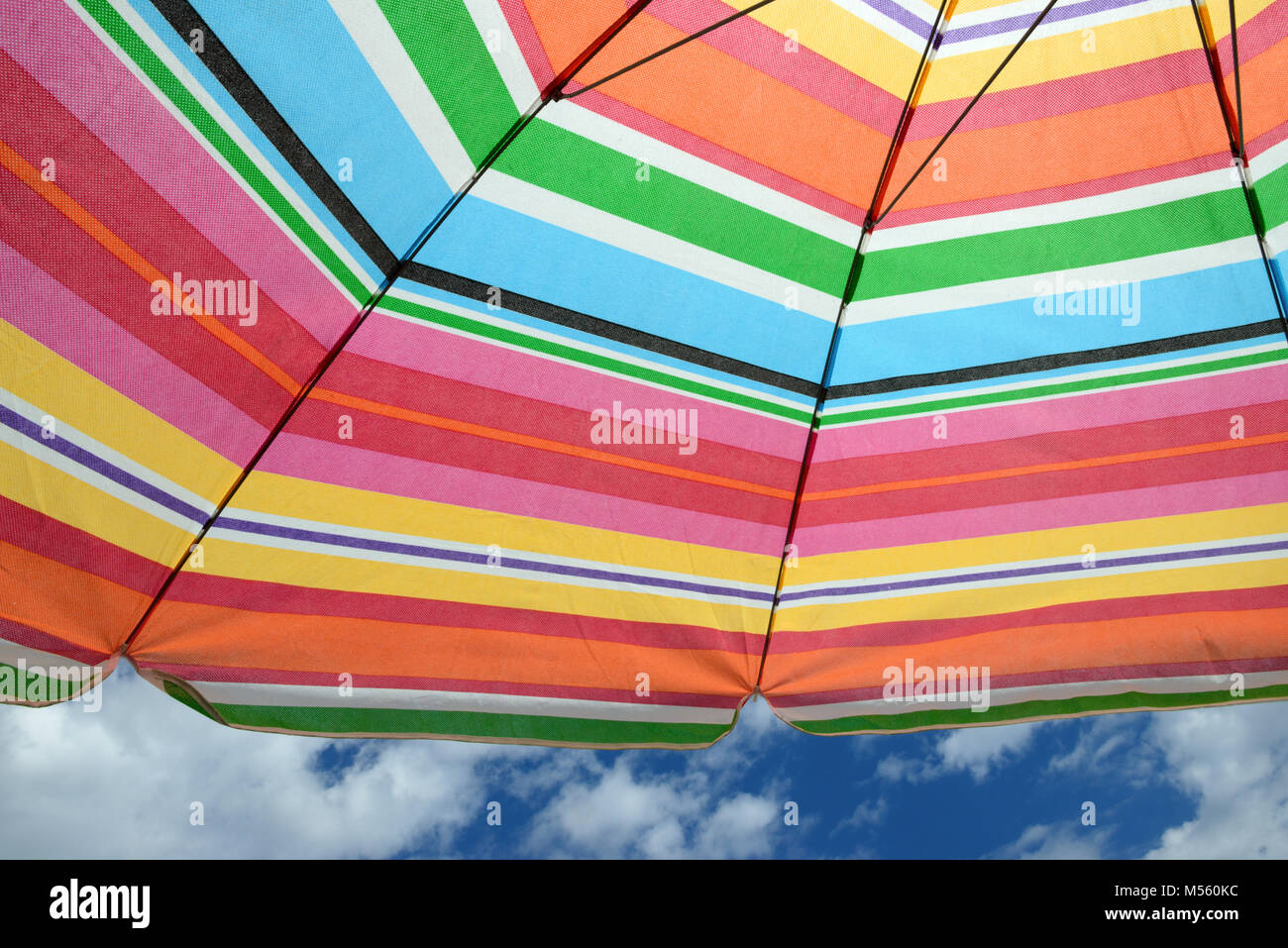 Close-up bright multicolor striped beach parasols in backlit of summer ...