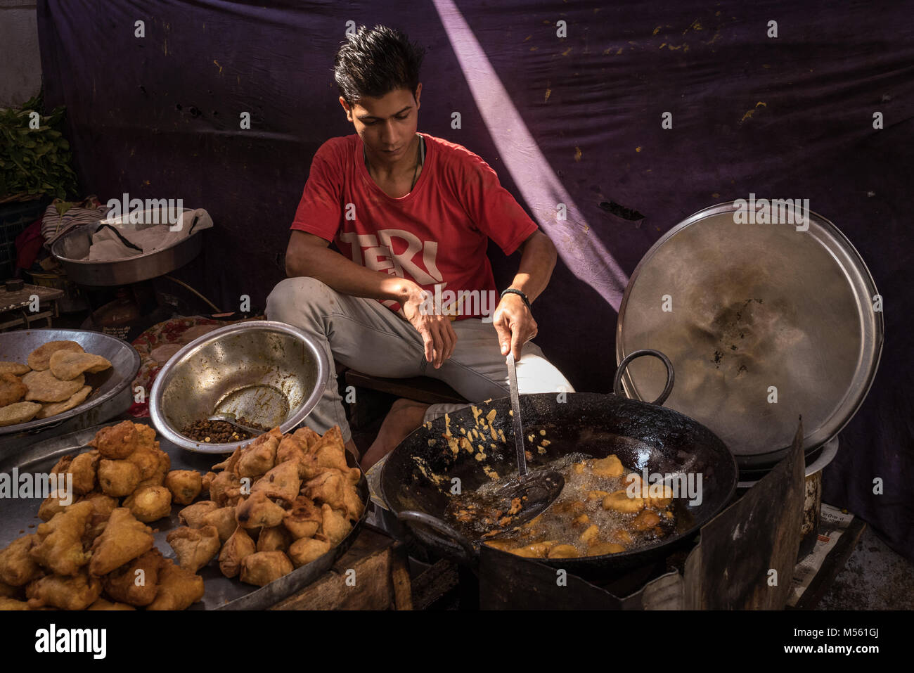 A man deep-frying samosas in an outdoor food stall in Varanasi, India ...