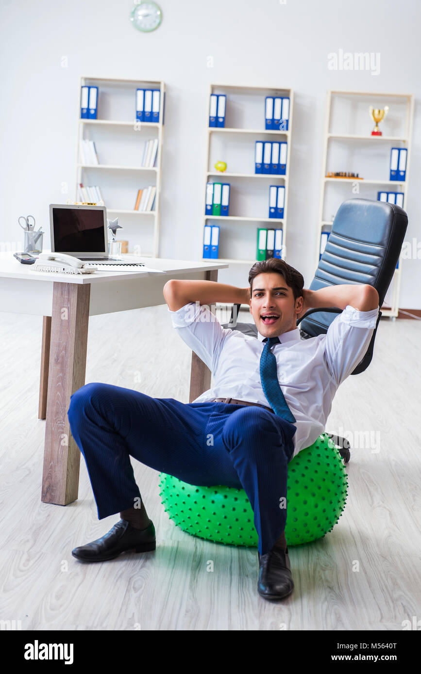 Young businessman doing sports stretching at workplace Stock Photo - Alamy