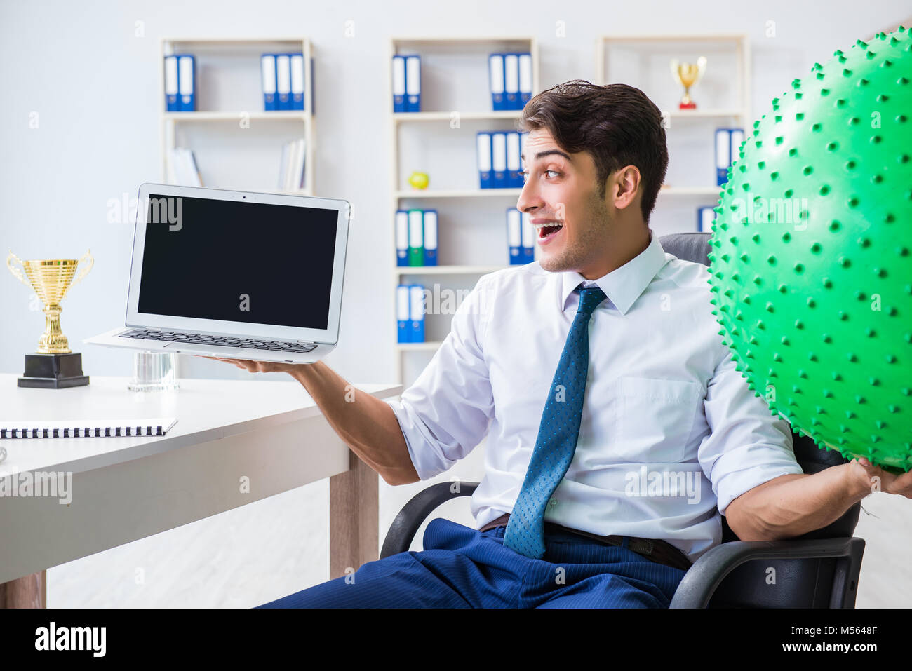 Young businessman doing sports stretching at workplace Stock Photo - Alamy