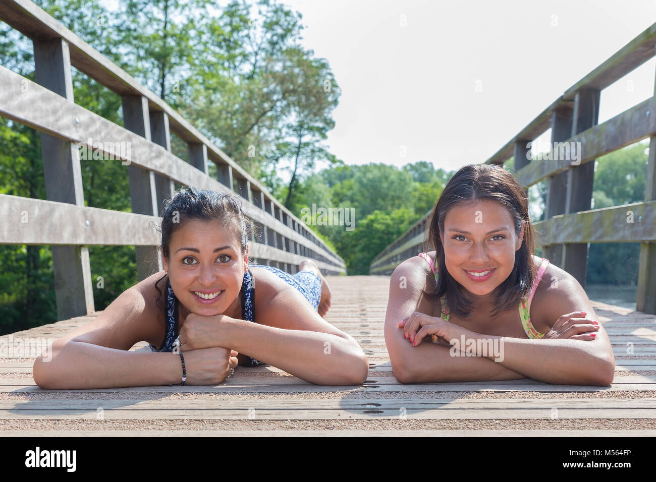 Two friends lying together on wooden bridge Stock Photo - Alamy