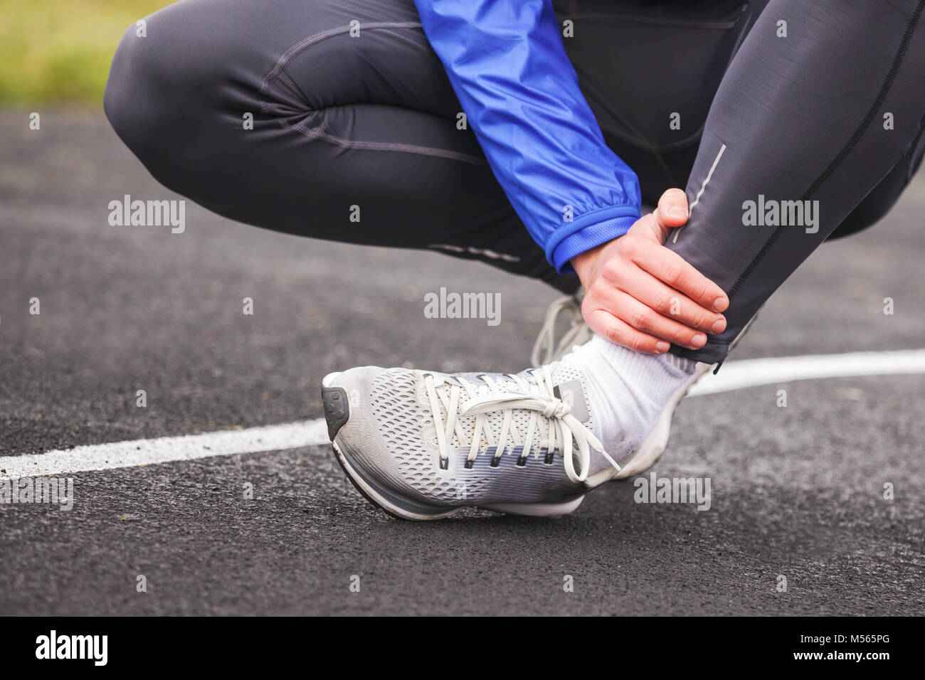 Cropped shot of a young man holding his ankle in pain while running ...