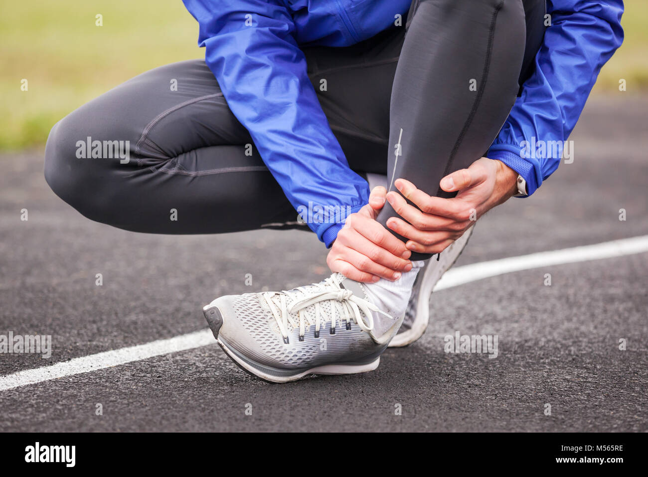 Cropped shot of a young man holding his ankle in pain while running ...