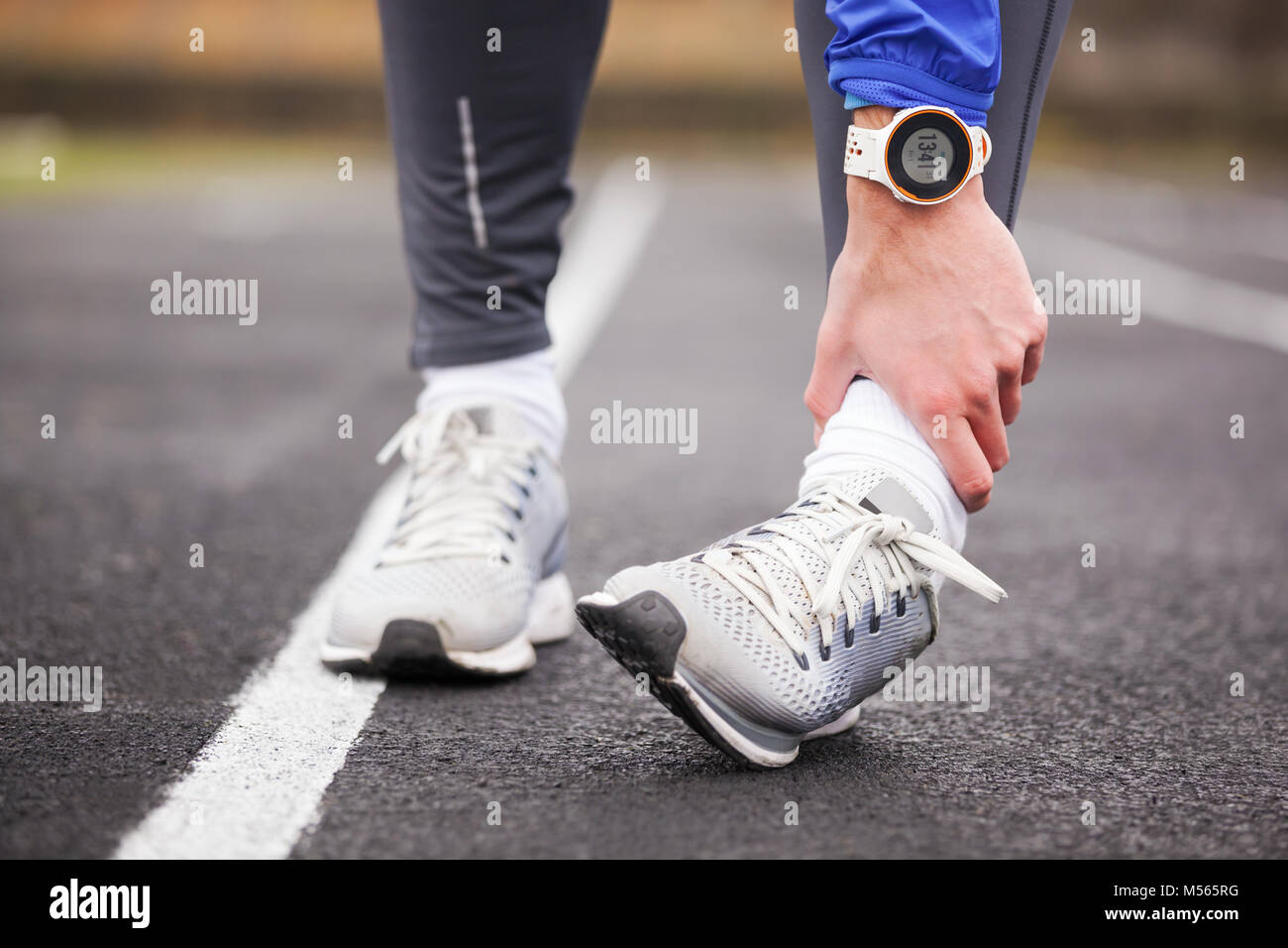 Cropped shot of a young man holding his ankle in pain while running ...