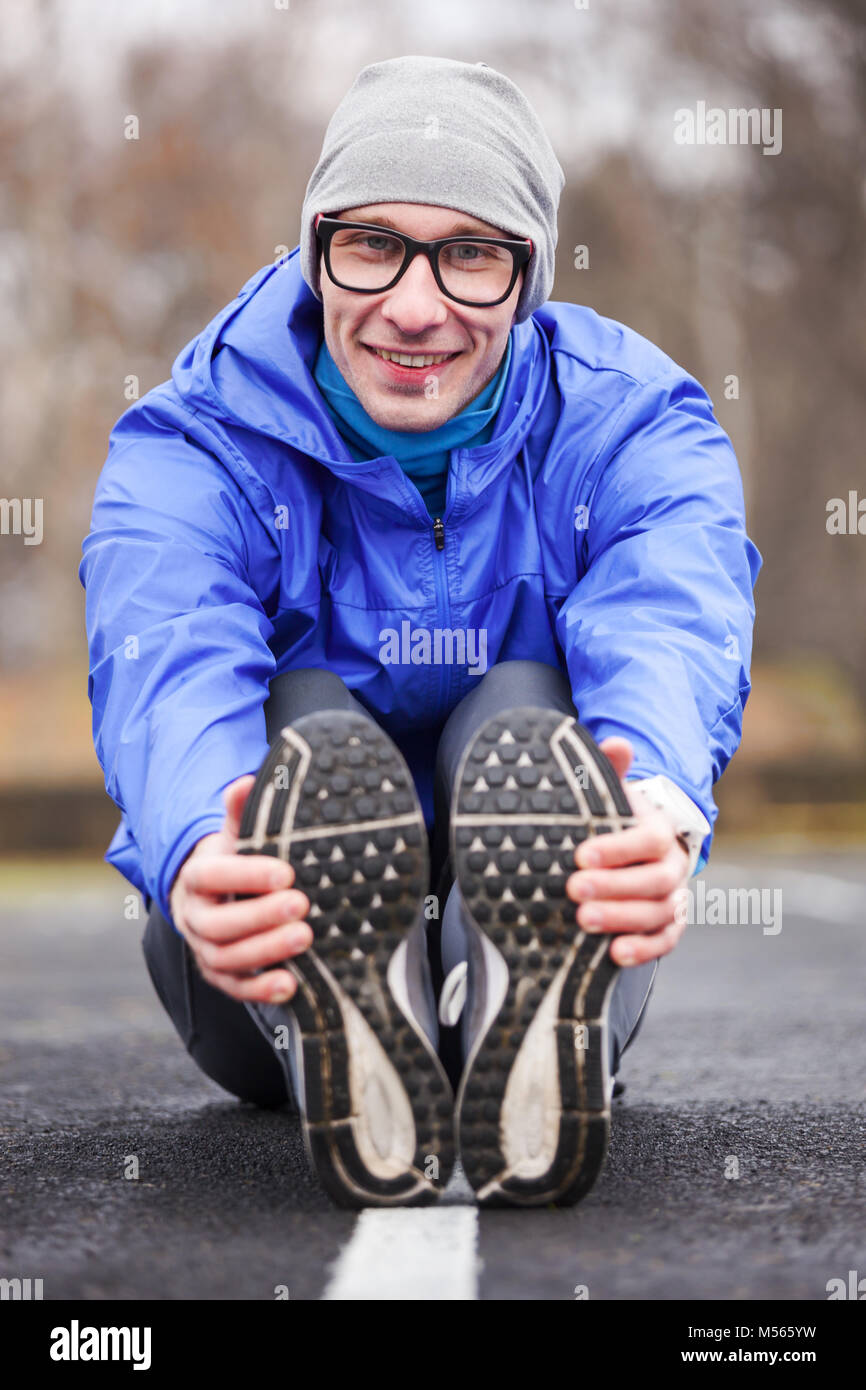 Shot of a young handsome professional runner stretching outdoors Stock ...