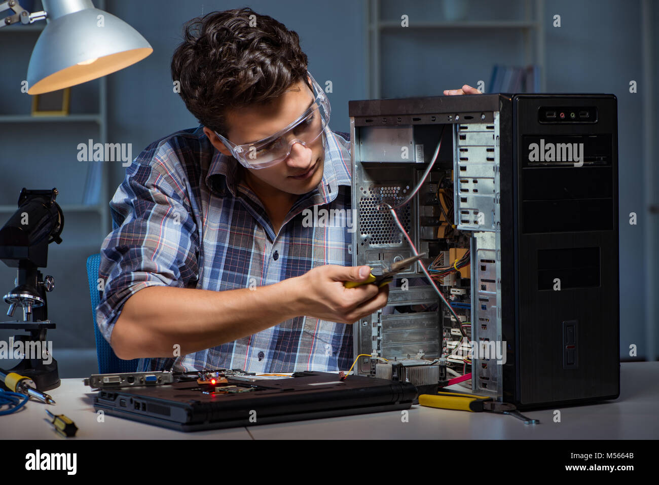 Man repairing computer desktop with pliers Stock Photo - Alamy