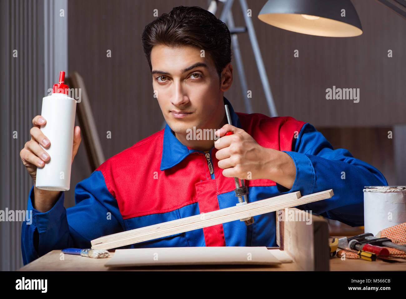 Young man gluing wood pieces together in DIY concept Stock Photo - Alamy
