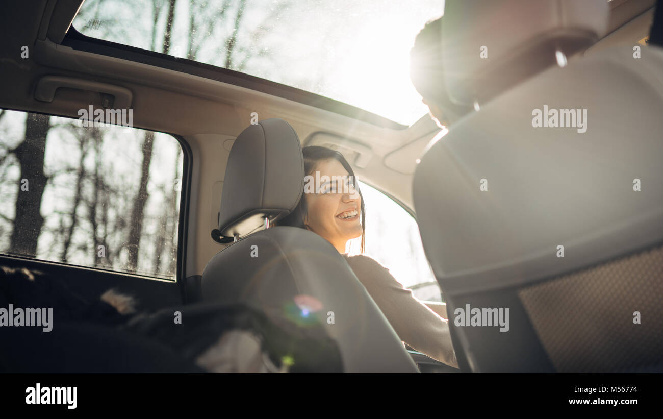 Young woman in a car,female driver looking at the passenger and smiling ...