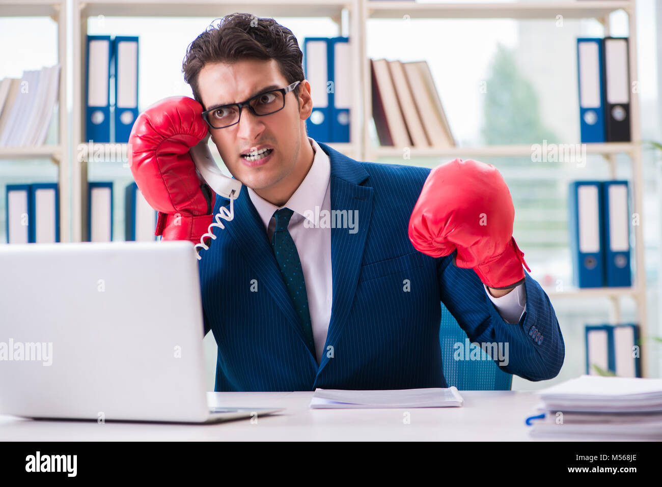 Businessman with boxing gloves angry in office Stock Photo - Alamy