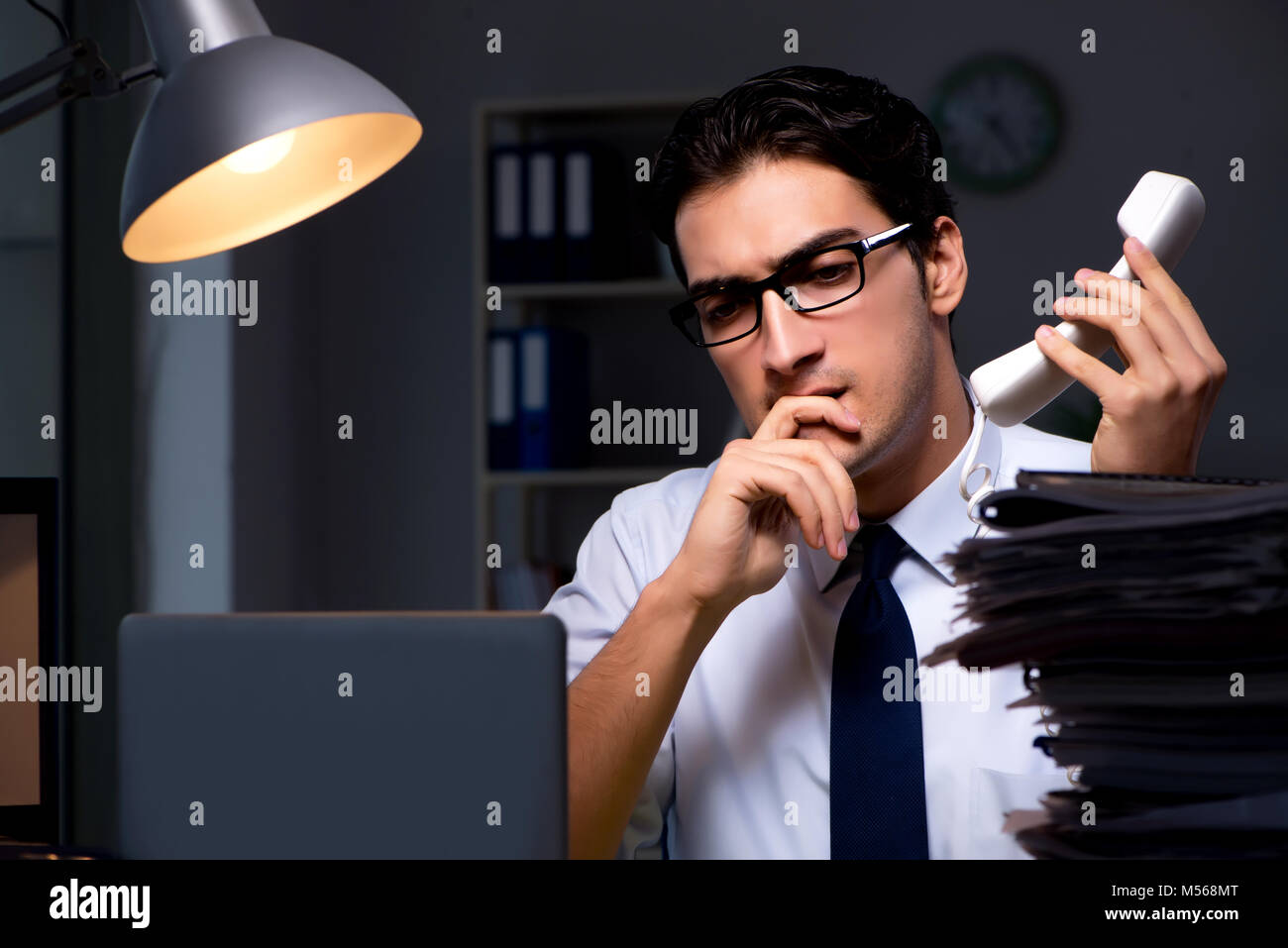 Young businessman working overtime late in office Stock Photo - Alamy