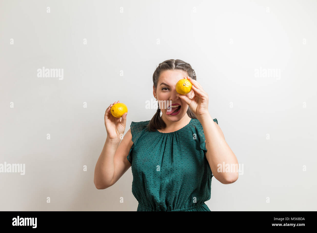 Hilarious girl makes faces while eating lemons fruits Stock Photo - Alamy