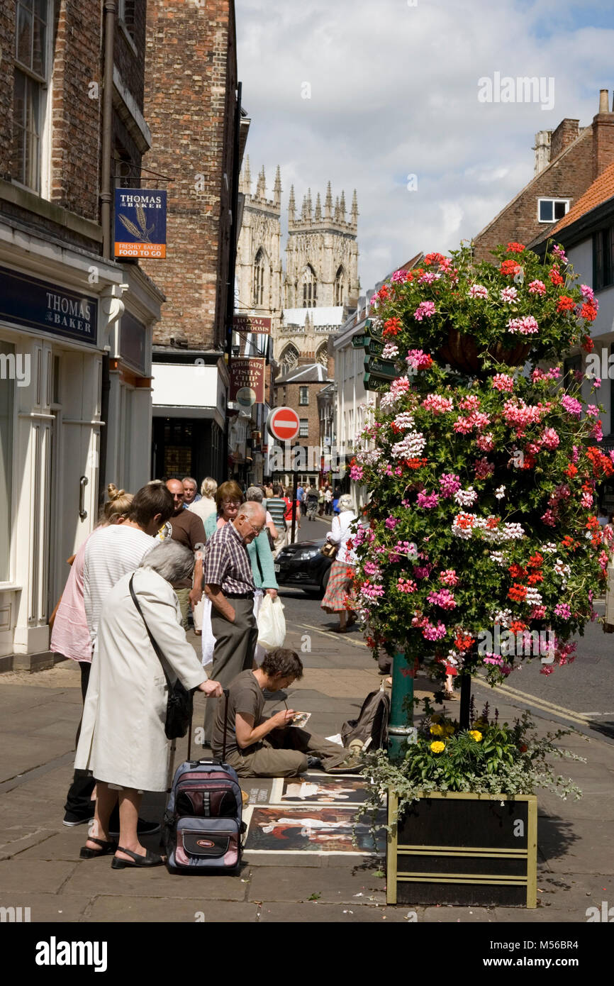 Passers-by watch a street artist in King's Square, York, England, UK ...
