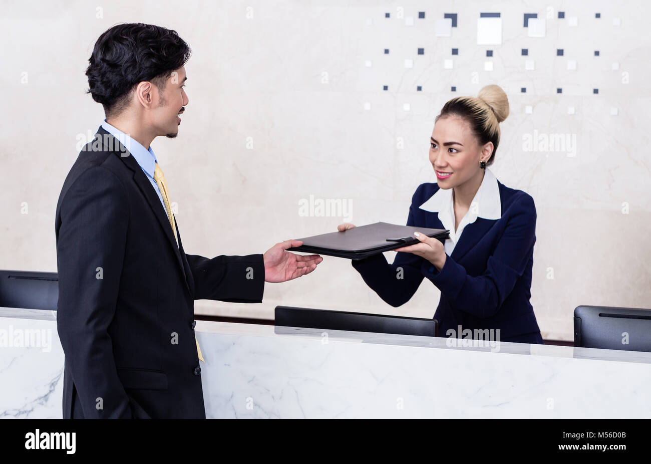 Job Applicant at business front desk giving his documents to ...