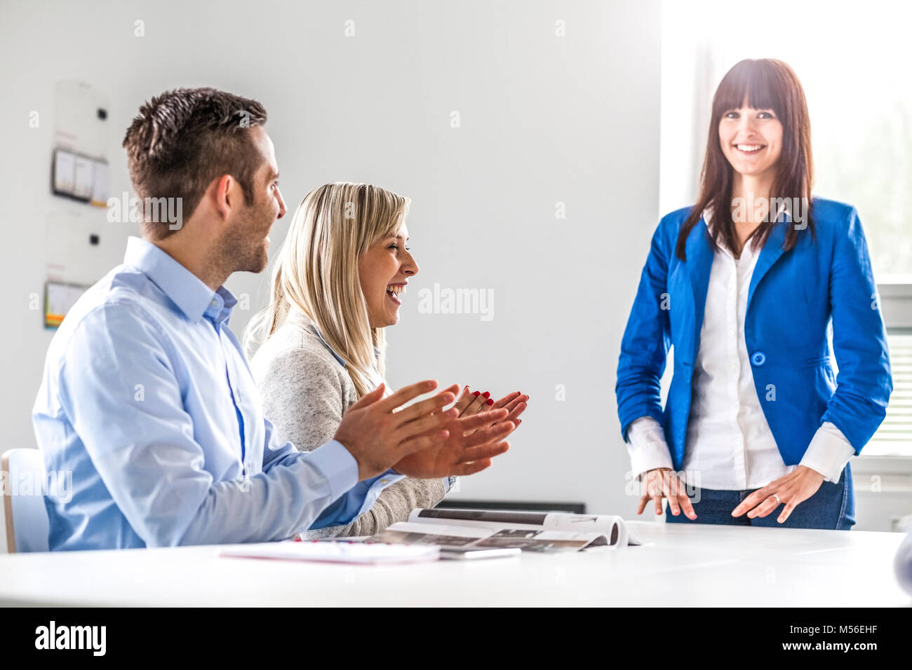Business associates applauding female colleague in board room Stock ...