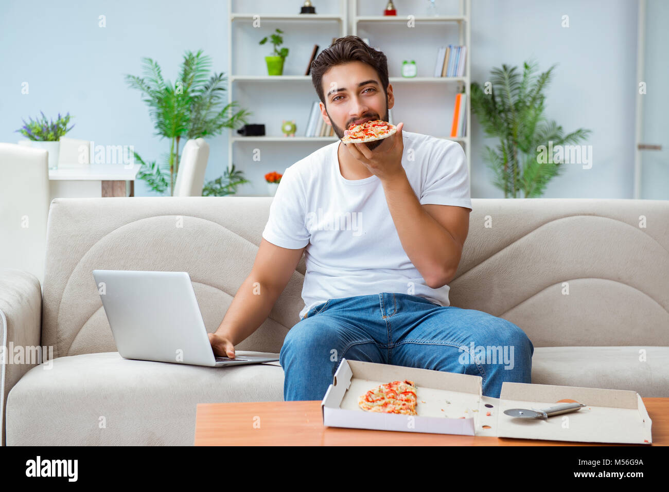 Man eating pizza having a takeaway at home relaxing resting Stock Photo ...