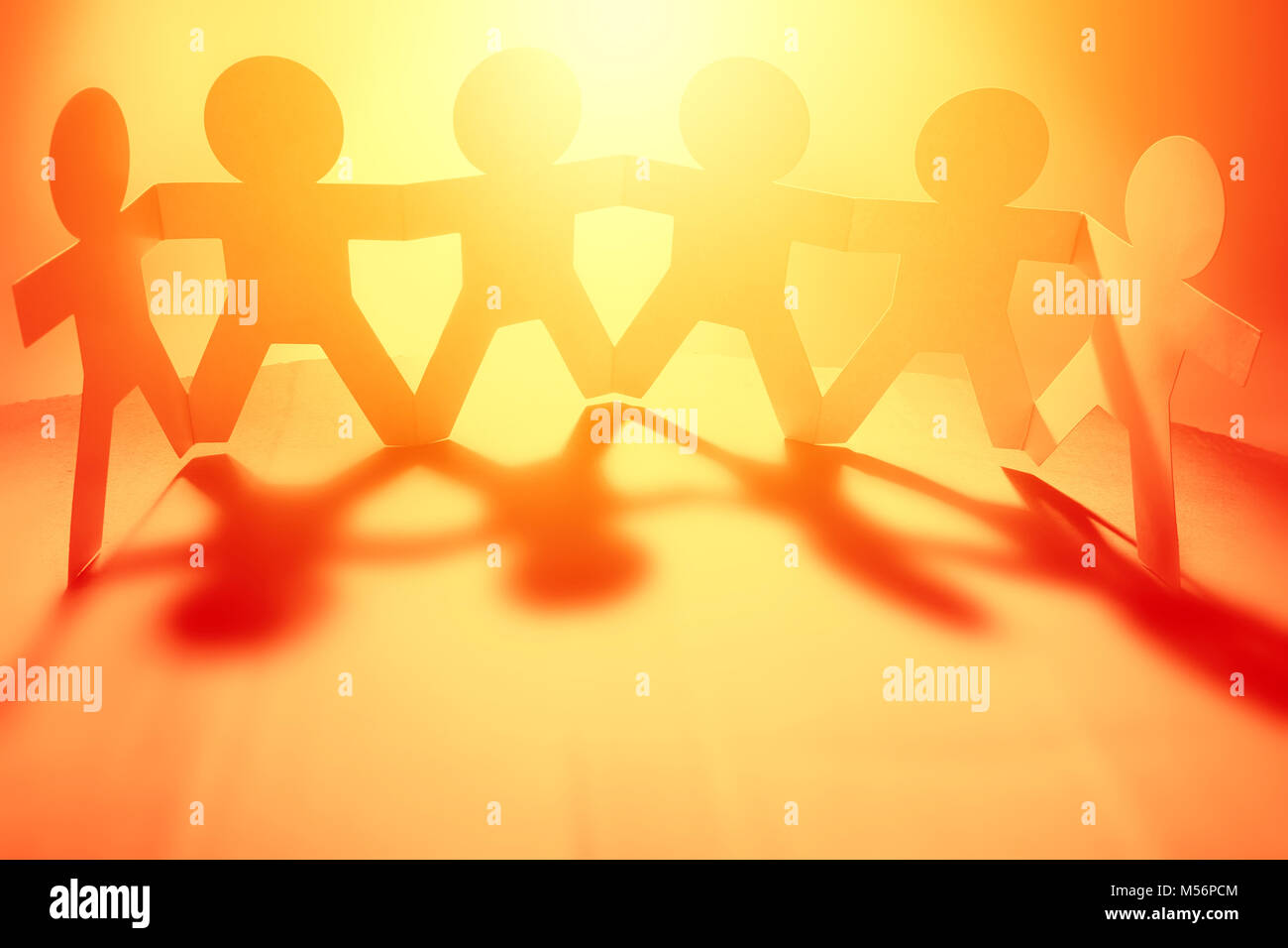 Team of paper chain people in a row holding hands Stock Photo - Alamy
