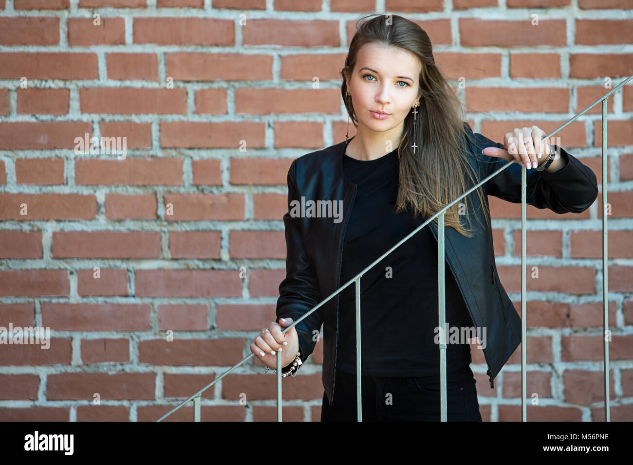 Portrait of a beautiful young woman against a brick wall background ...