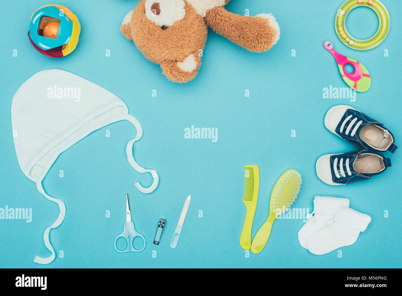 top view of teddy bear and baby clothes with equipment isolated on blue ...