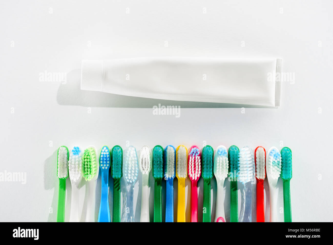 top view of colorful toothbrushes and tube of toothpaste, on white ...