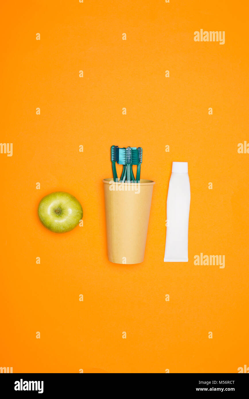 top view of apple, toothbrushes in paper cup and tube of toothpaste ...