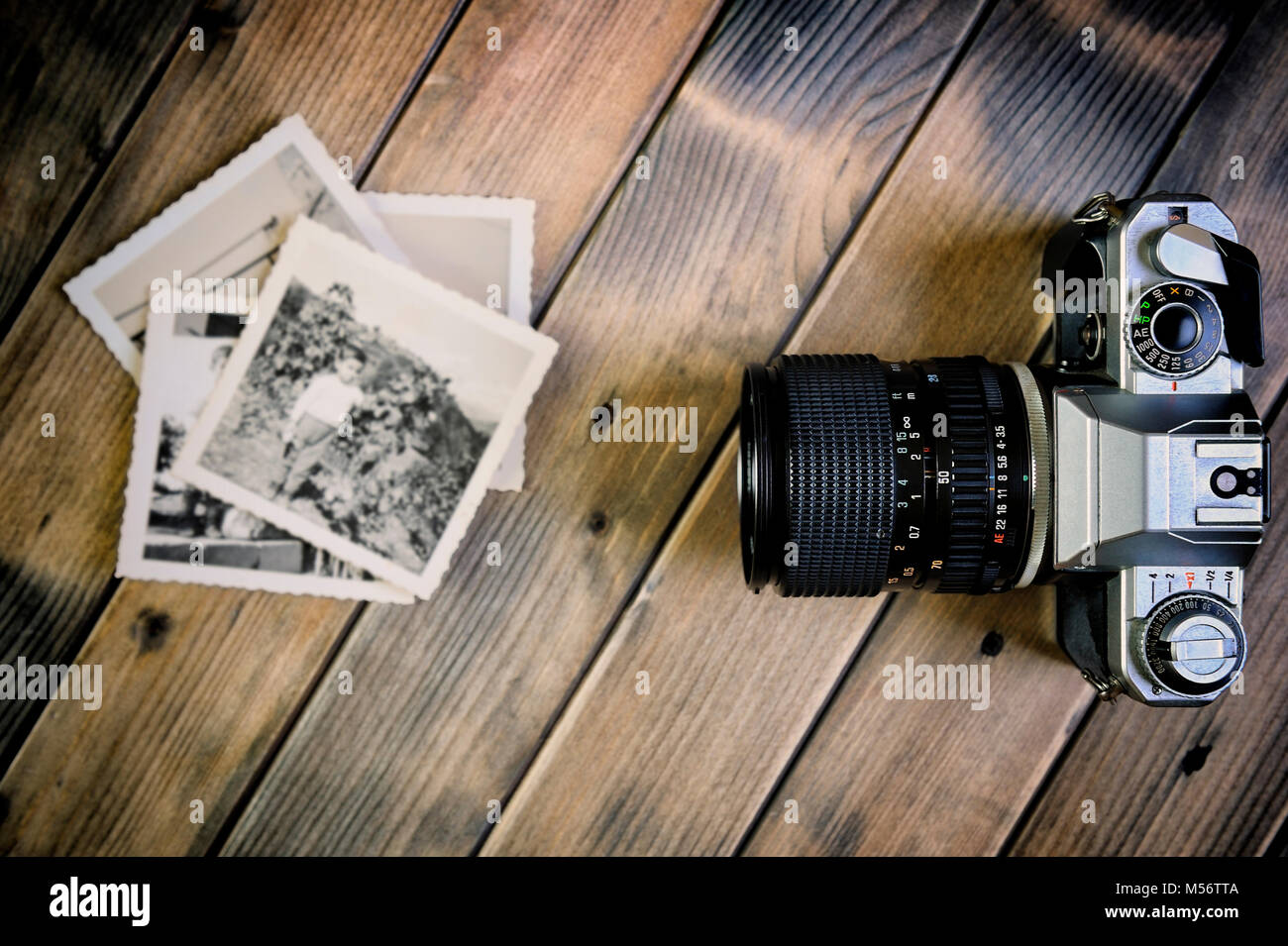 Top view of vintage photographs and 35mm film camera on a rustic wooden ...