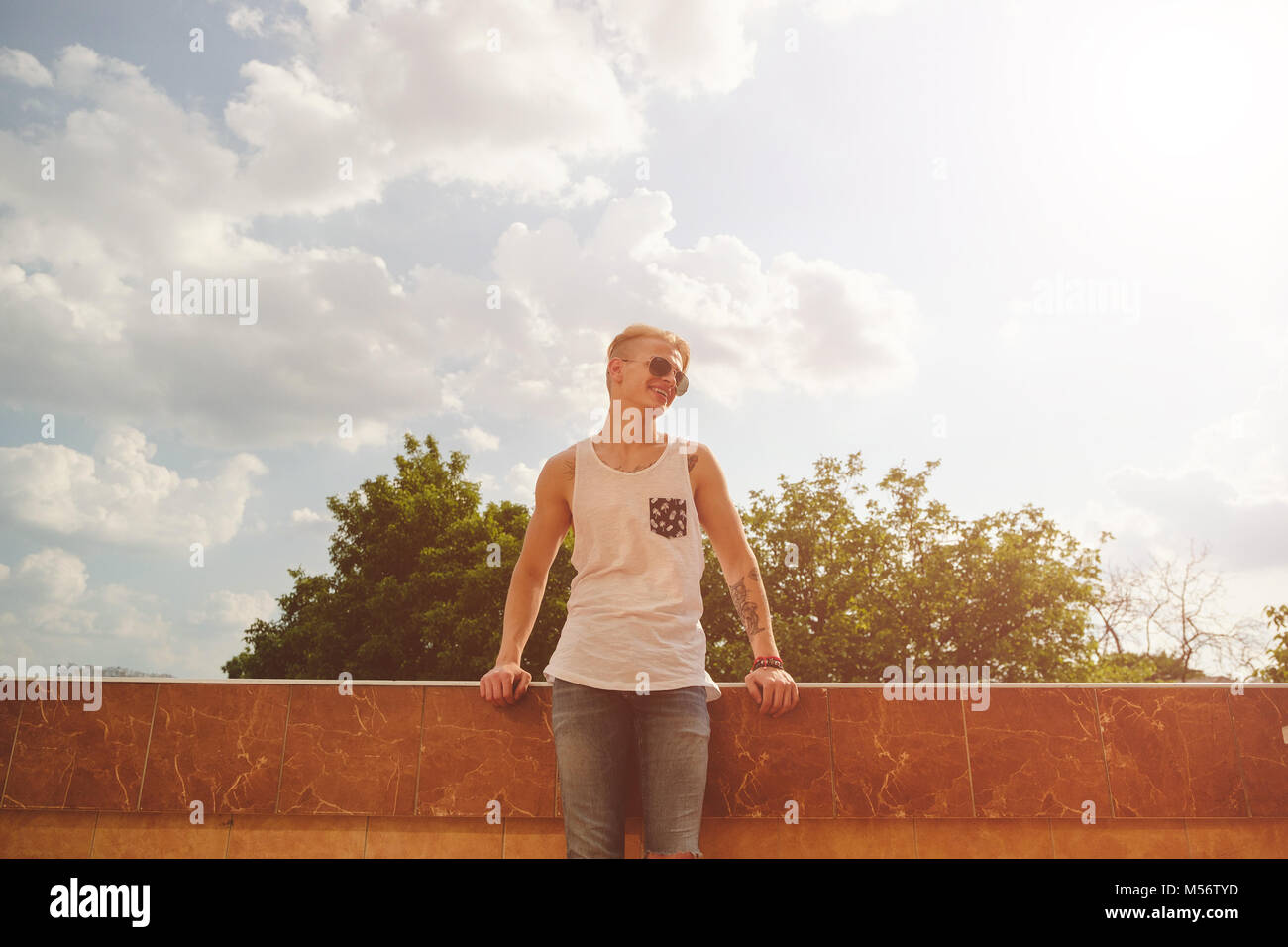 Young man relaxing, enjoying a sunny day while standing on a bui Stock ...