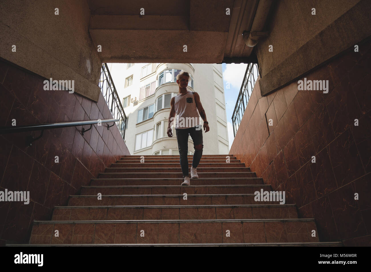 Young man getting down stairs in pedestrian subway Stock Photo - Alamy