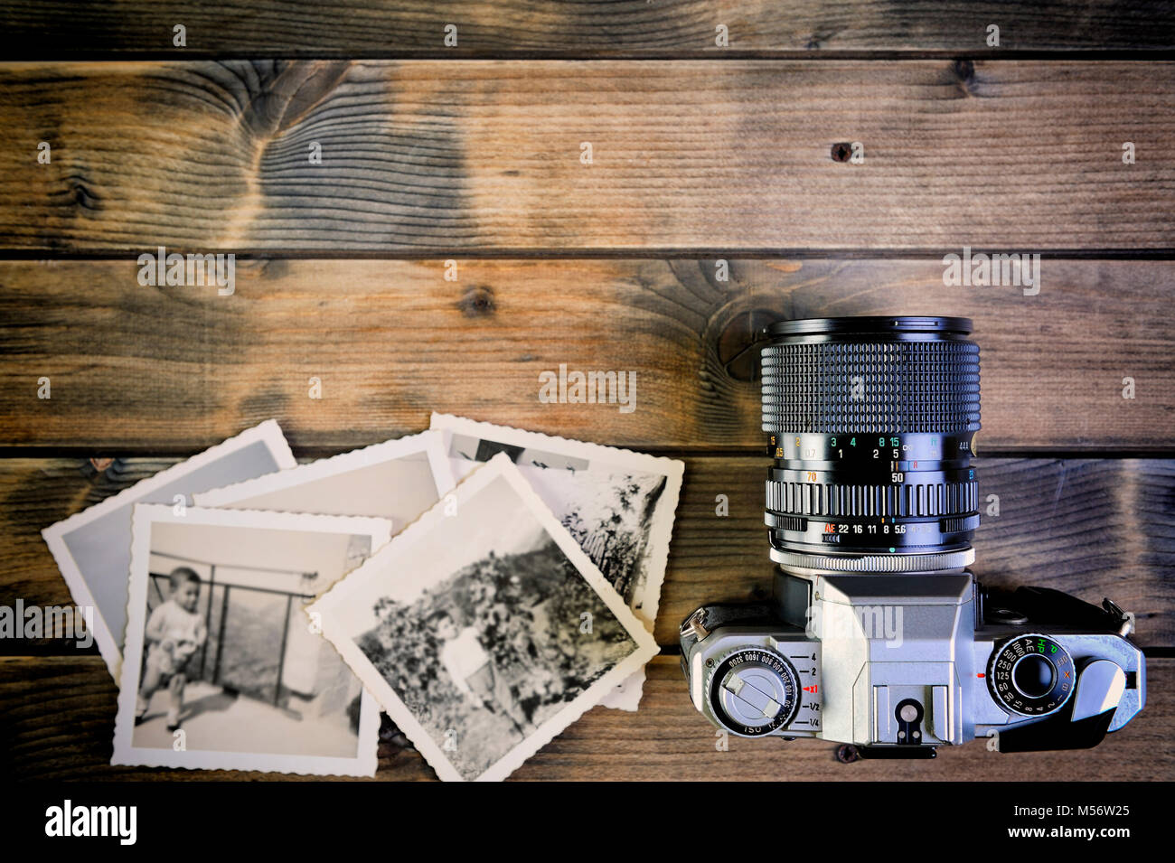 Top view of vintage photographs and 35mm film camera on a rustic wooden ...