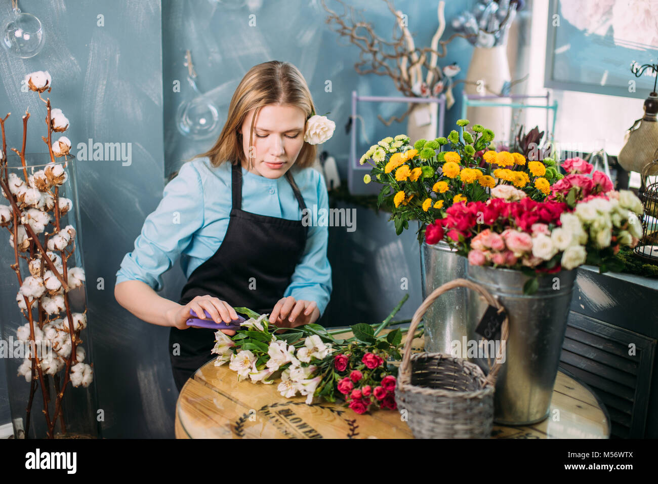 blond female cutting bad flowers at flower market Stock Photo - Alamy