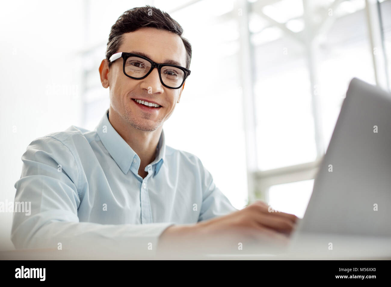 Cheerful worker working on his laptop Stock Photo - Alamy