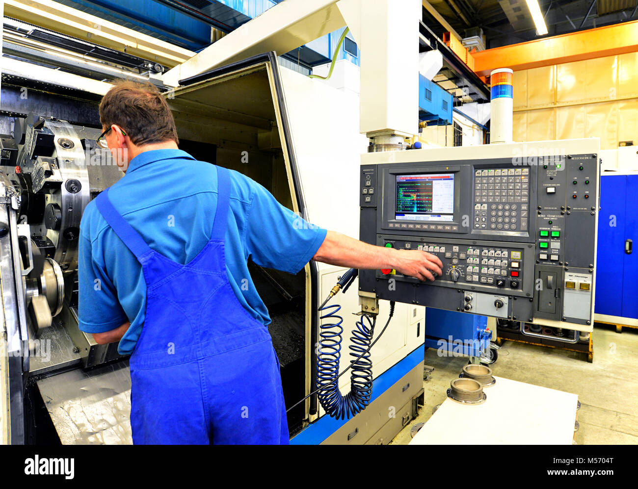 factory worker operates a cnc milling machine for the production of ...