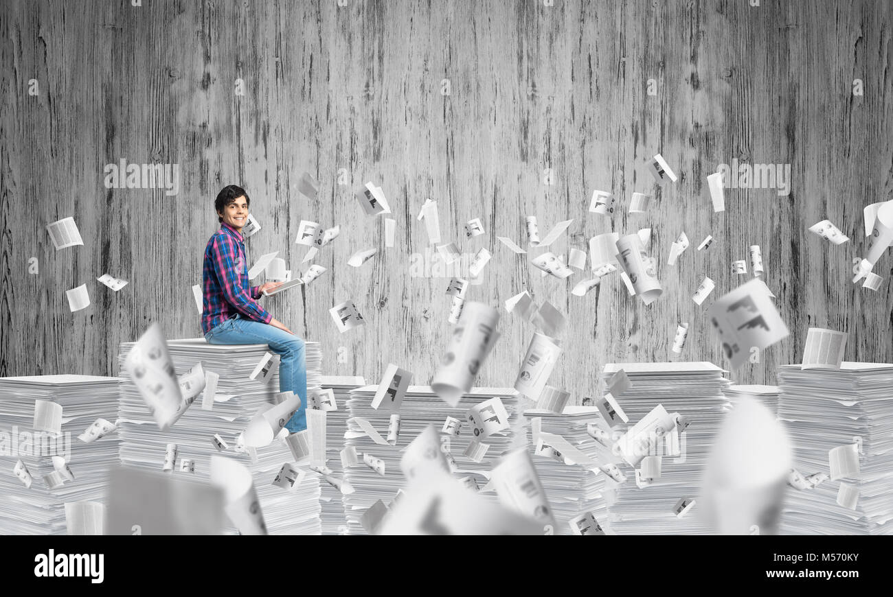 Attractive man sitting on pile of paper documents Stock Photo - Alamy
