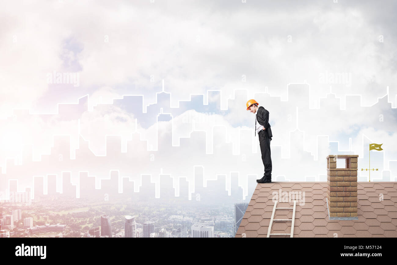 Engineer man standing on roof and looking down. Mixed media Stock Photo ...