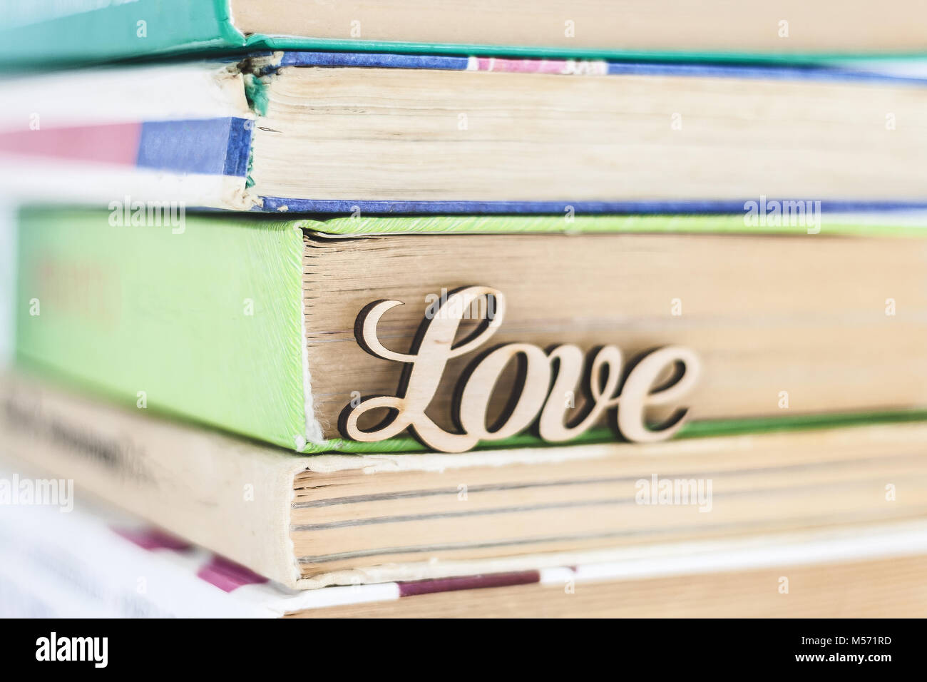 on a stack of old books wooden word love Stock Photo - Alamy