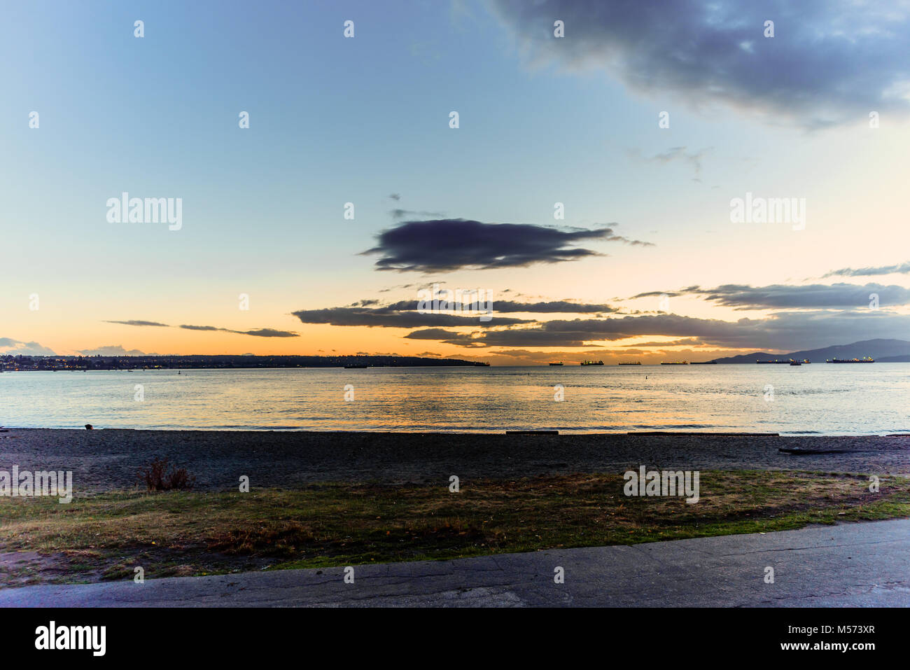 View of the evening ocean with lights of ships, mountains and clouds ...