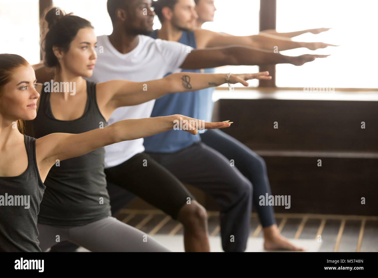 Group of yogi people in Warrior Two pose Stock Photo - Alamy